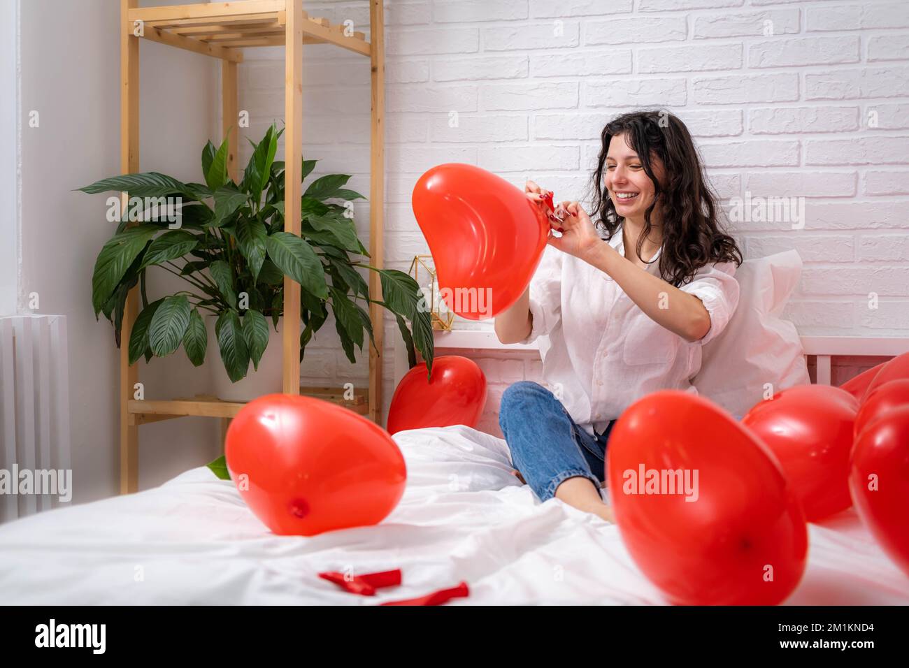 Girl is blowing air balloon at home Handsome brunette girl inflating ...