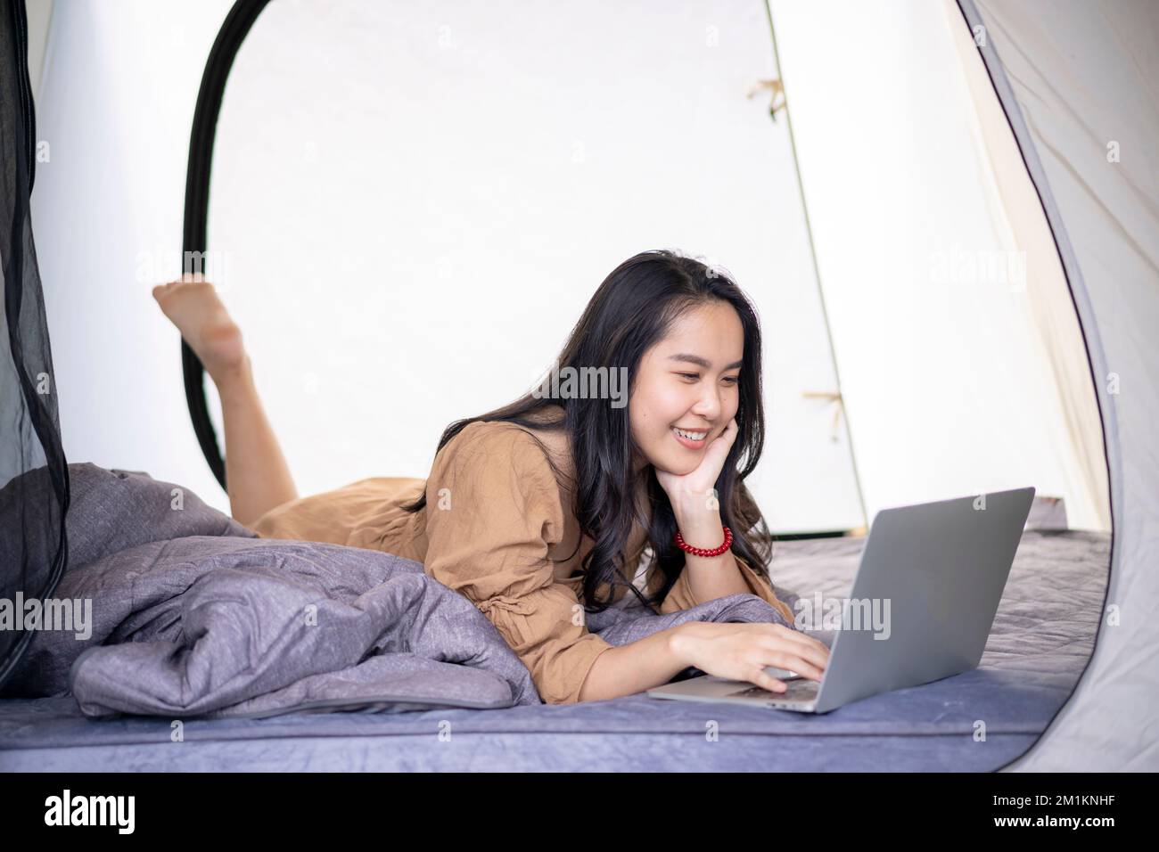 Young Asian woman using computer laptop while vacation in the tent at ...