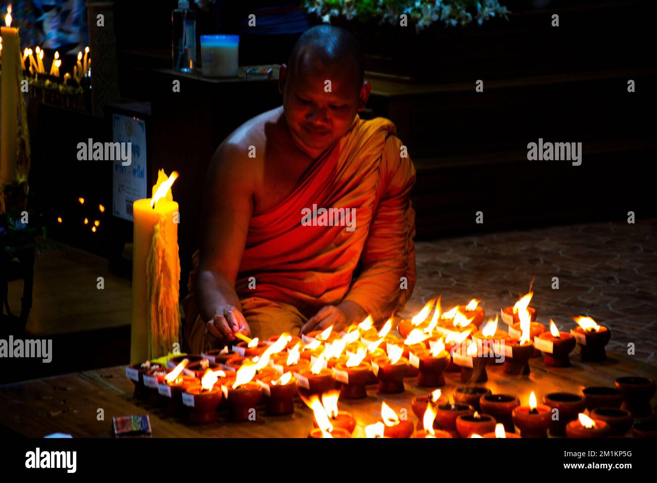 Thai young monk light a fire candle for respect praying buddha god ...