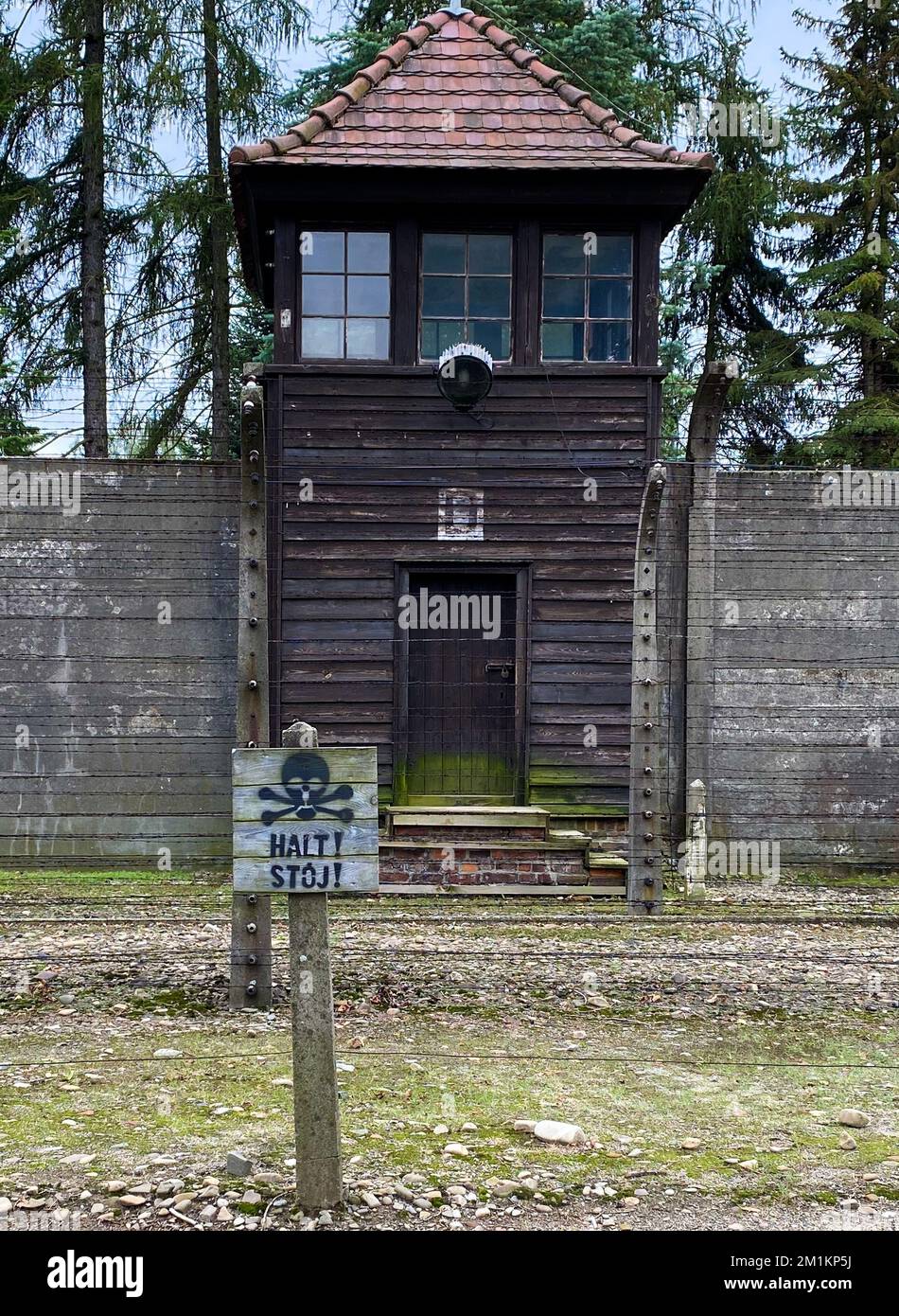 A wooden stop danger sign in front of a guard tower at the Auschwitz ...