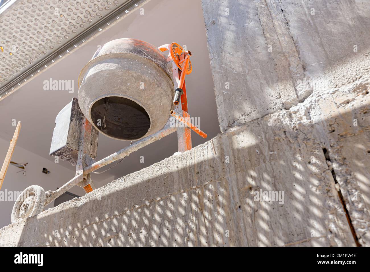 Shot from bellow on cement mixer machine placed on balcony of building ...