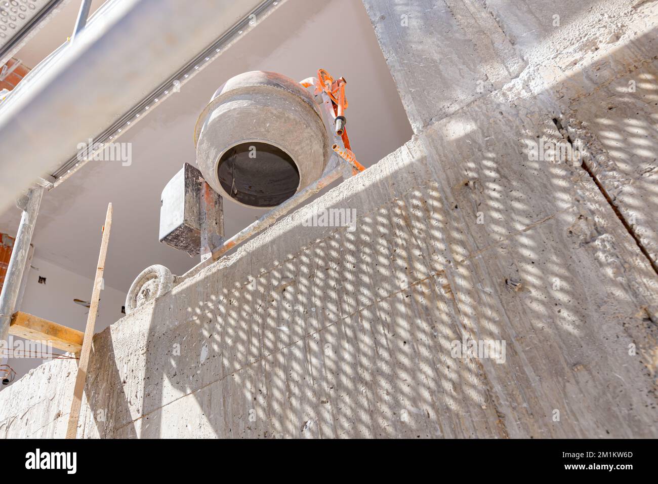 Shot from bellow on cement mixer machine placed on balcony of building ...