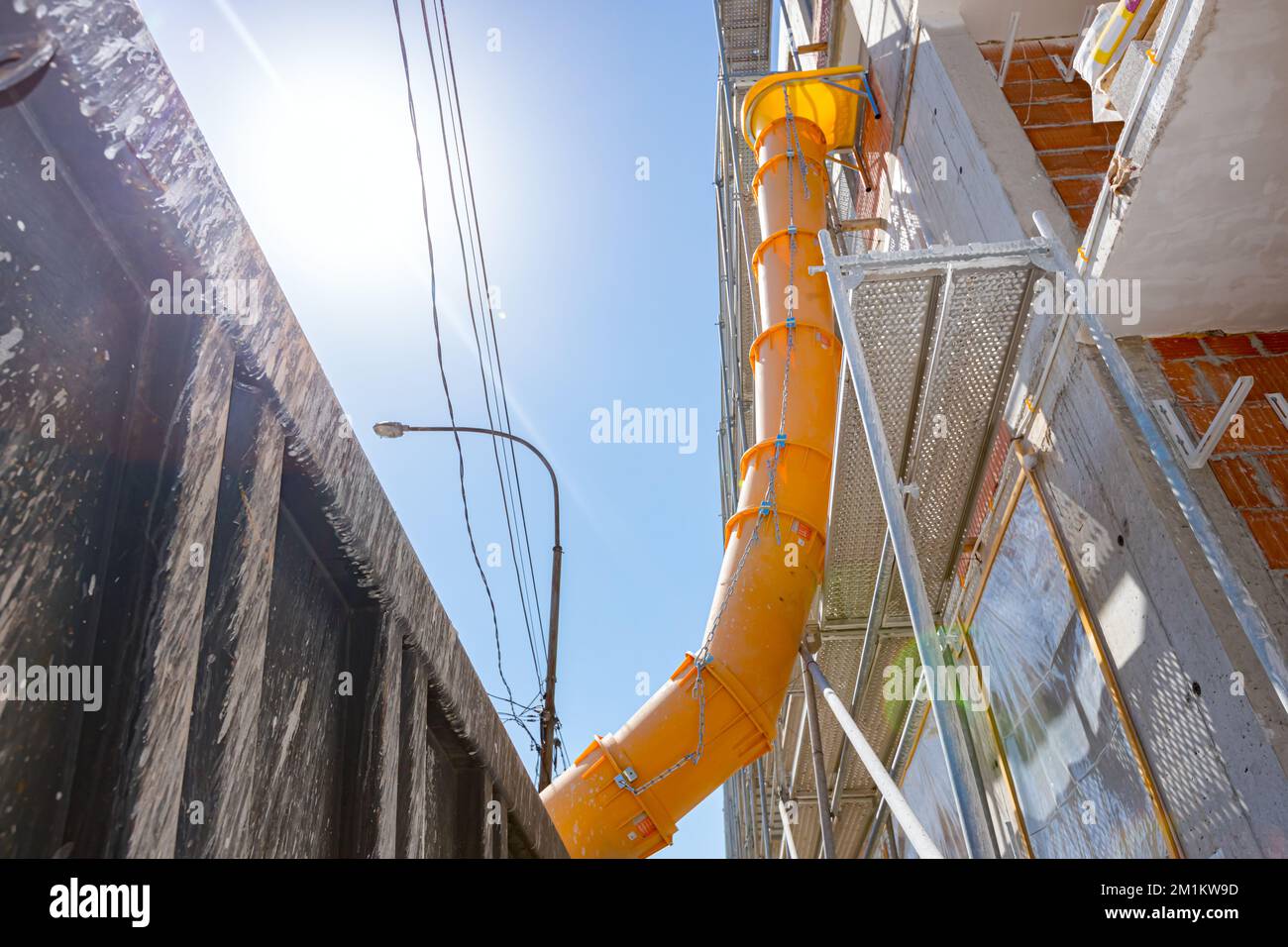 Shot from bellow on yellow long plastic tube placed next to building ...