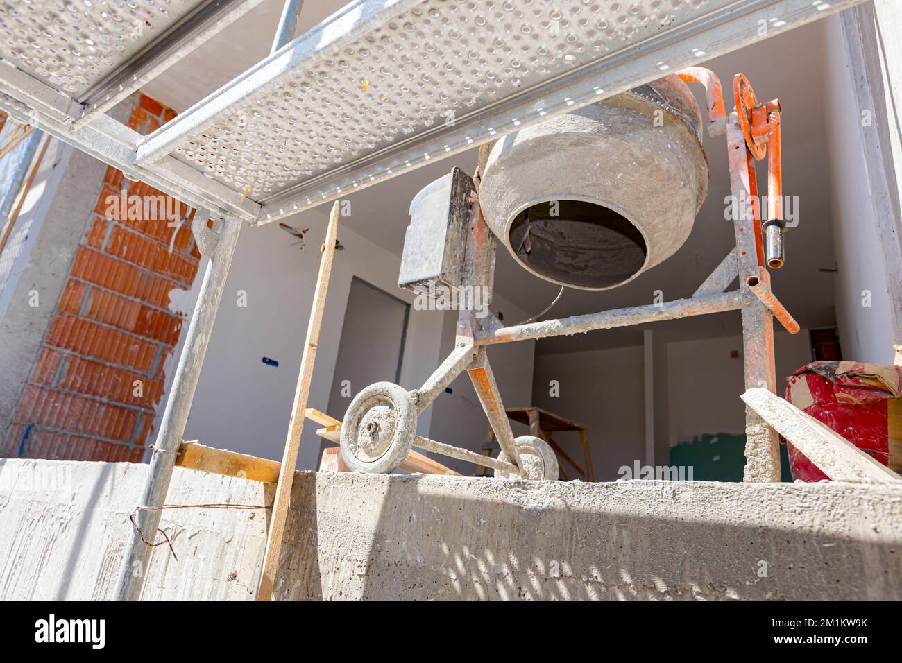 Shot from bellow on cement mixer machine placed on balcony of building ...