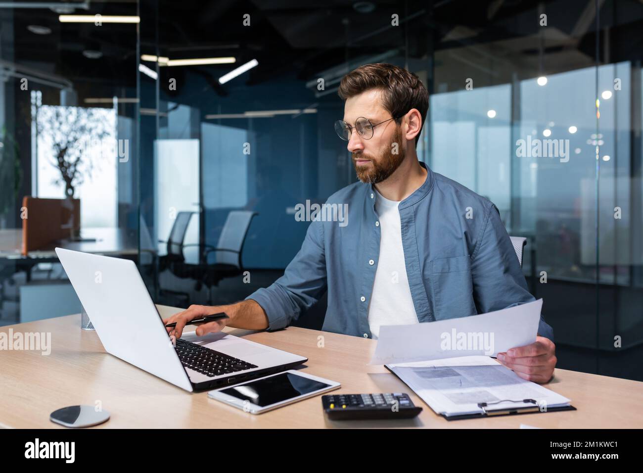 Serious and focused financier accountant on paper work inside office ...