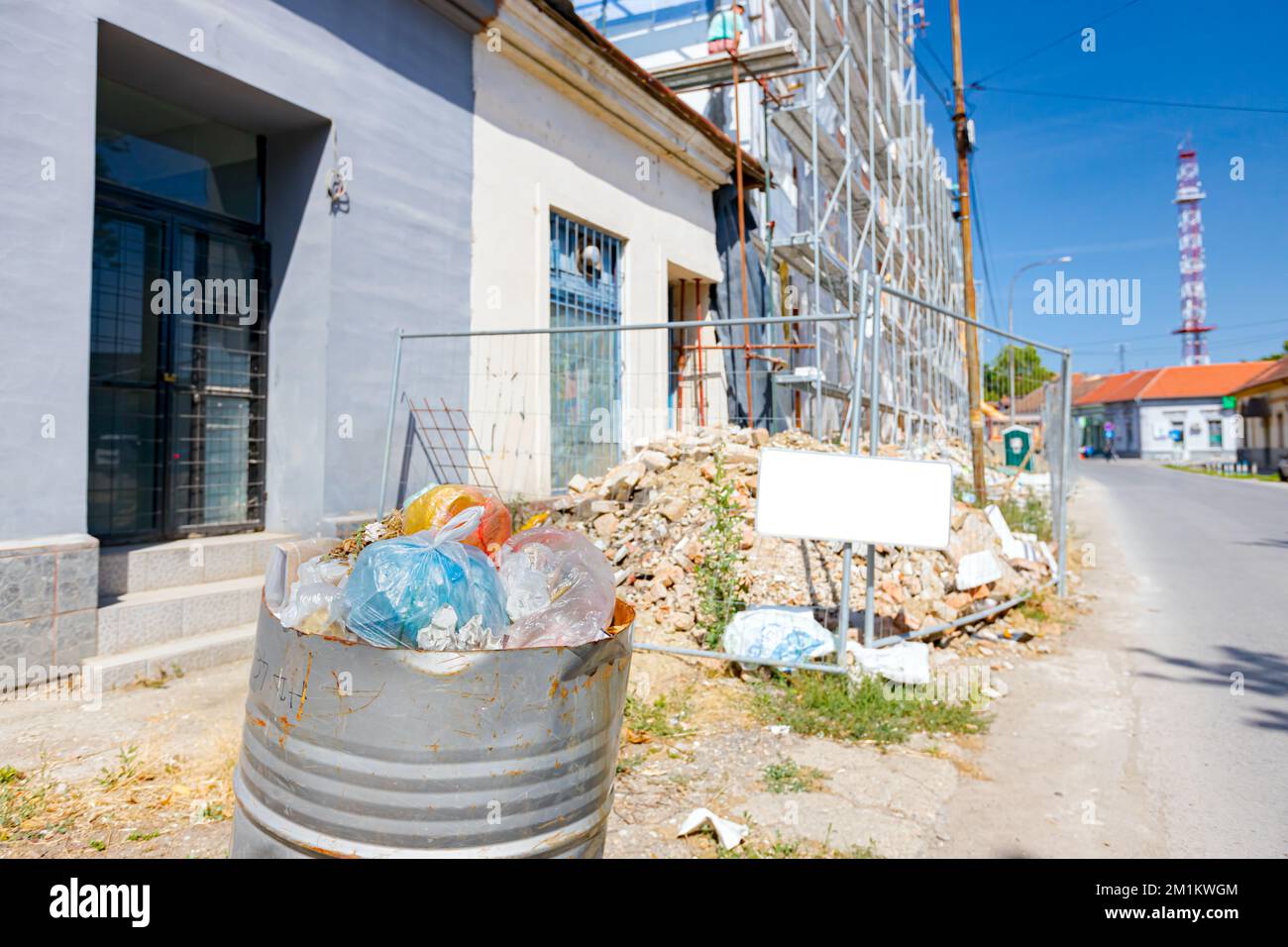 Makeshift trash bin, a cut metal barrel in front of the construction ...