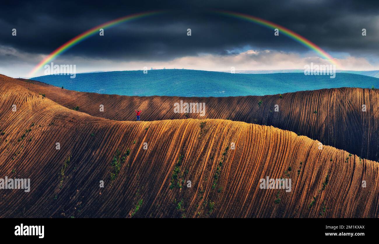 Rainbow and dramatic gray sky with clouds landscape. picturesque hilly ...