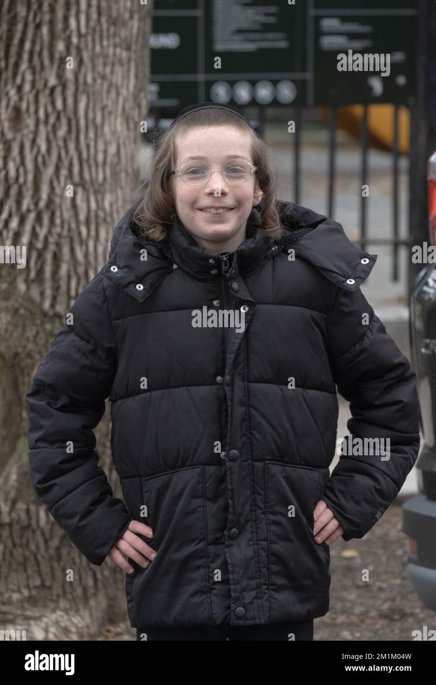 Posed portrait of a hasidic boy with long peyot and a smile. In ...