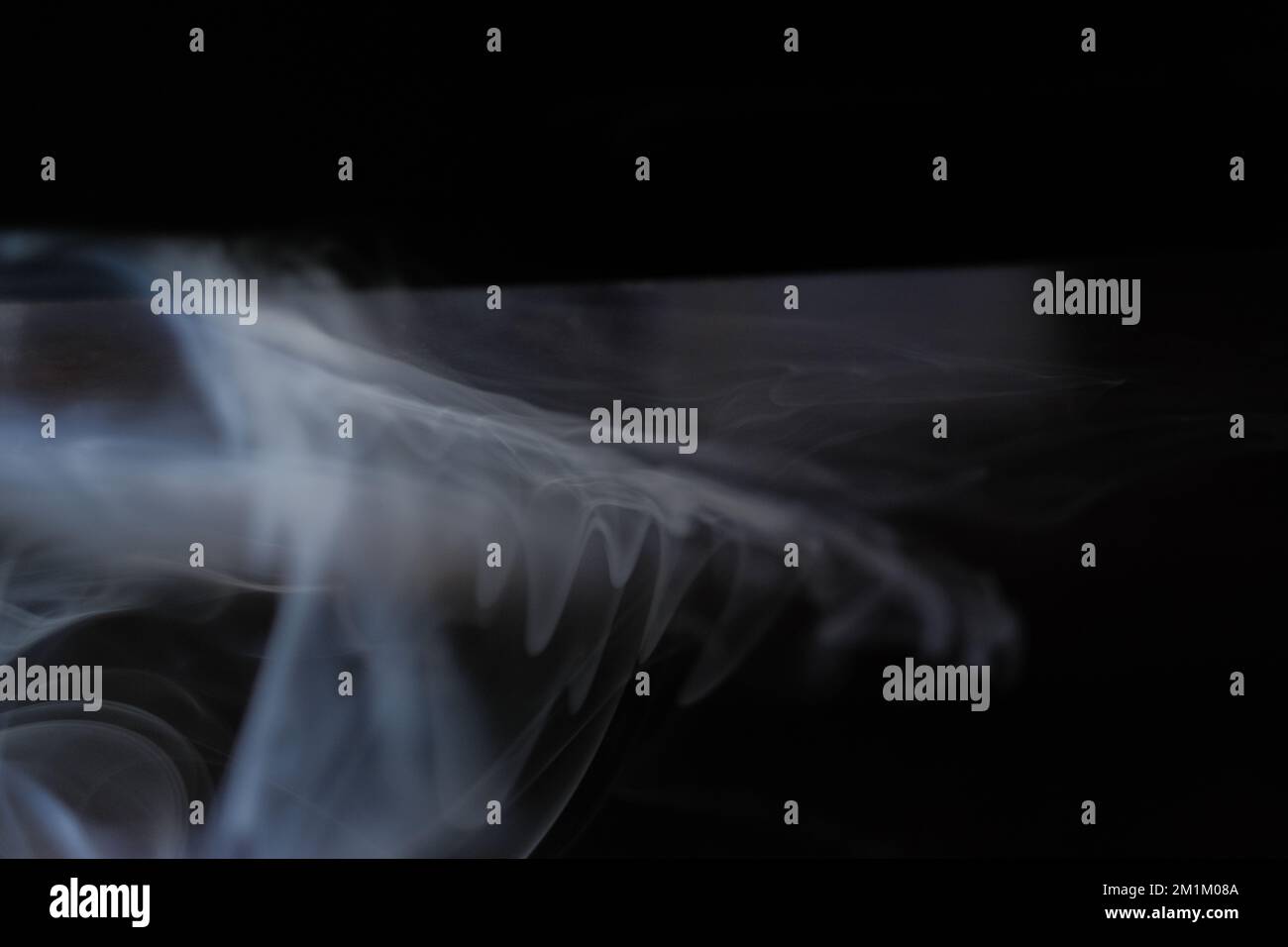 Graceful swirls of white incense smoke on black background. Vapor close ...