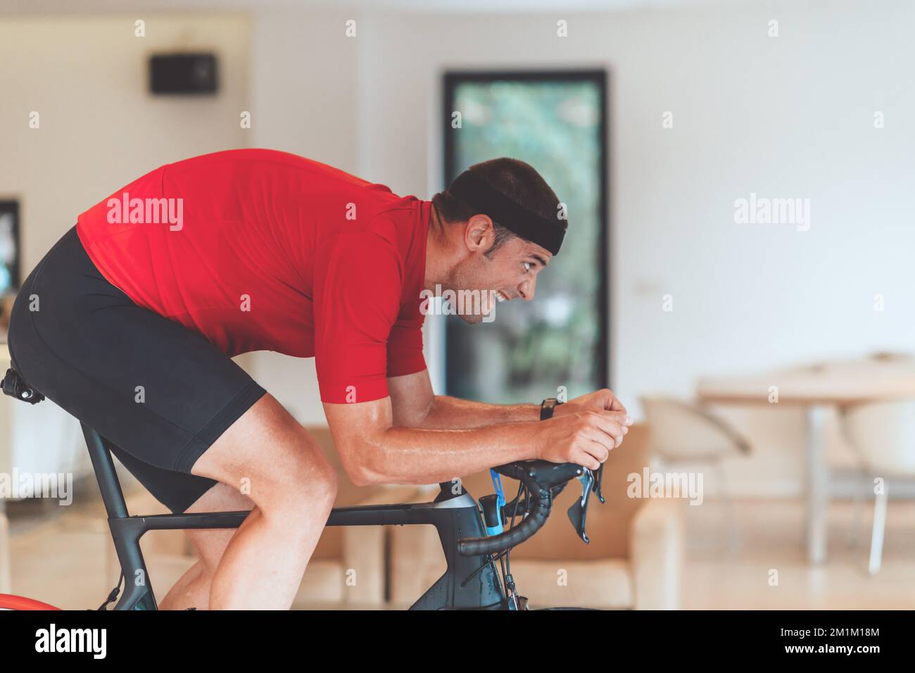 A man riding a triathlon bike on a machine simulation in a modern ...