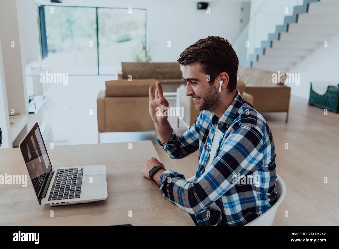 The man sitting at a table in a modern living room, with headphones ...