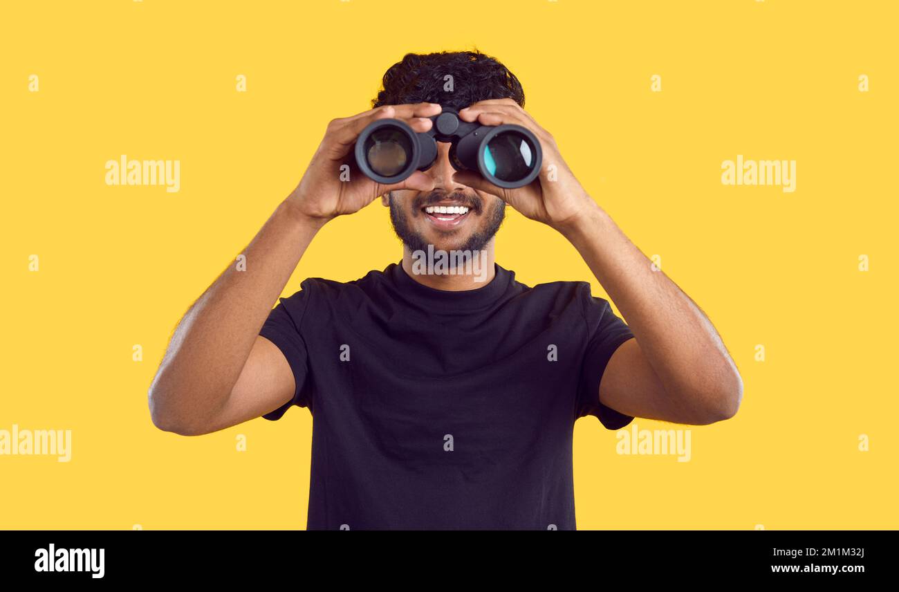 Happy ethnic man looking through binoculars looking for profitable ...