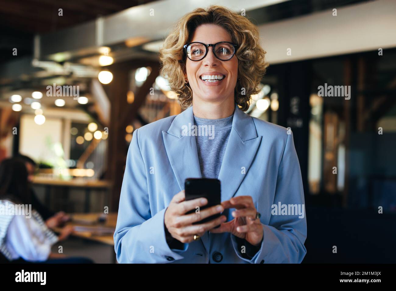 Mature business woman texting on a mobile phone in a workplace. Happy ...