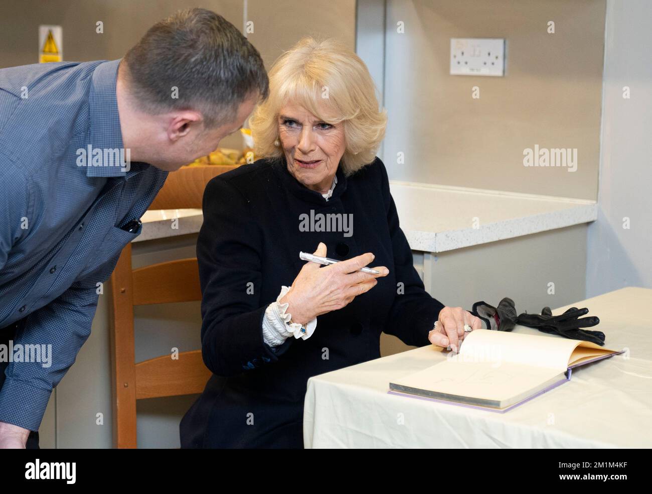 The Queen Consort signs the visitors book during a visit to the Emmaus ...