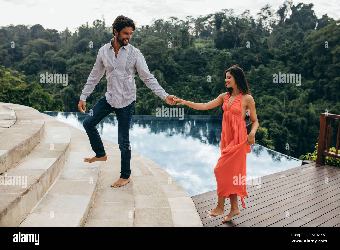 Portrait of young man and woman in love walking by swimming pool. Young ...