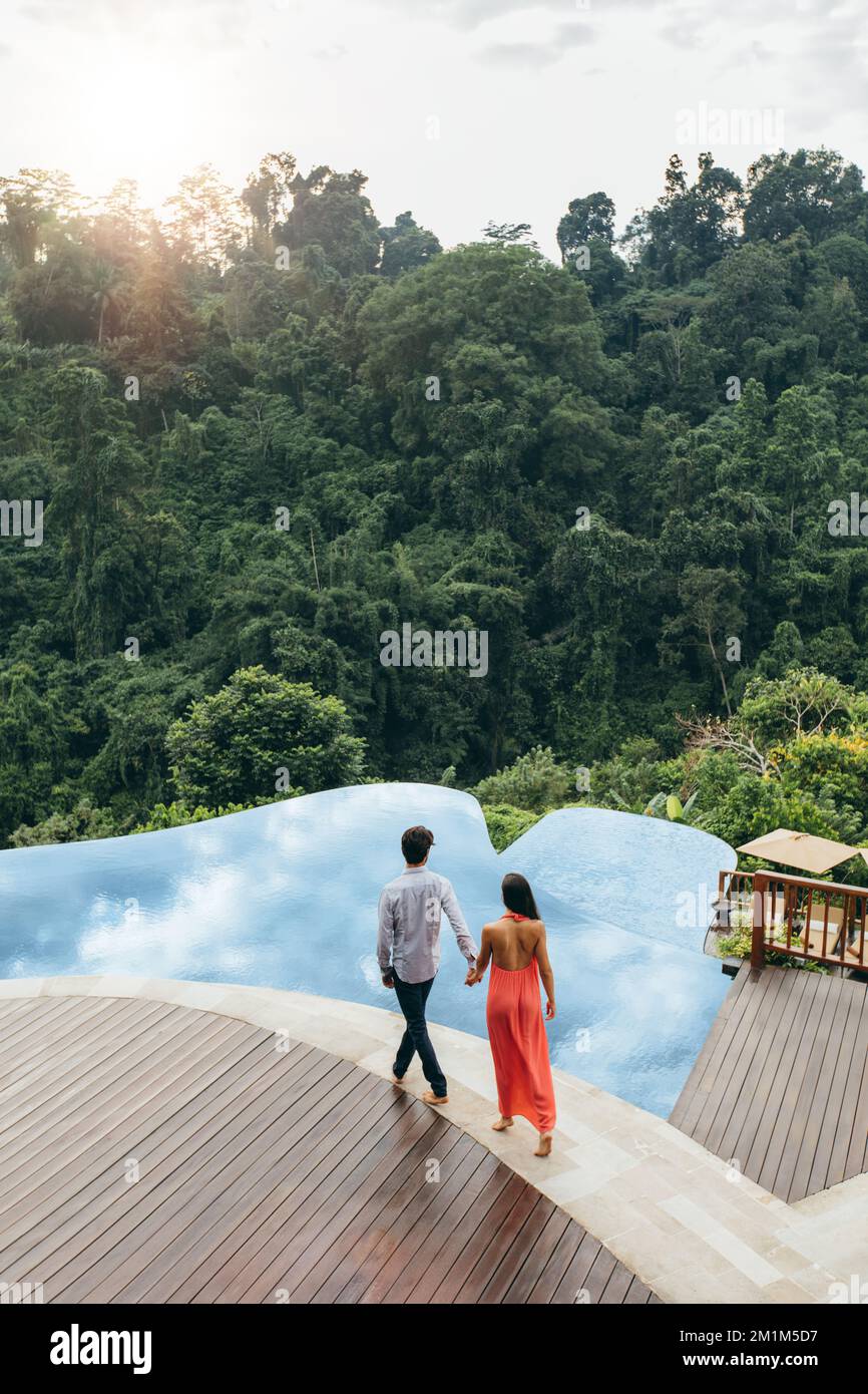 Aerial shot of young couple walking towards pool at luxury resort. Man ...