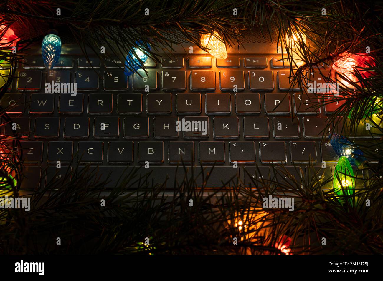 laptop keyboard surrounded by lights of a Christmas garland. Christmas ...