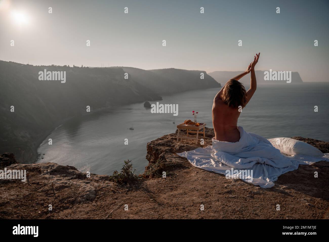 Woman wake up in bed wuth duvet and pillow over nature sea background ...