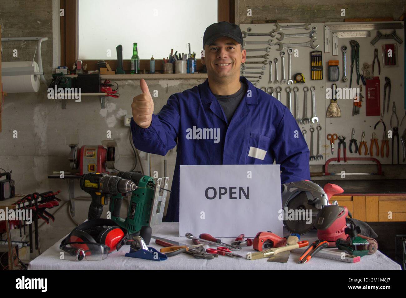 Image of a smiling handyman giving a thumbs up in his workshop with a ...