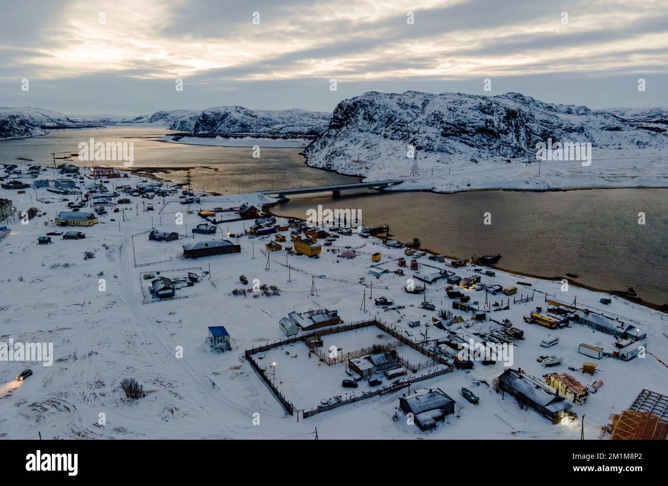 A dramatic wide angle view of black lava pebble beach with snow. Arctic ...