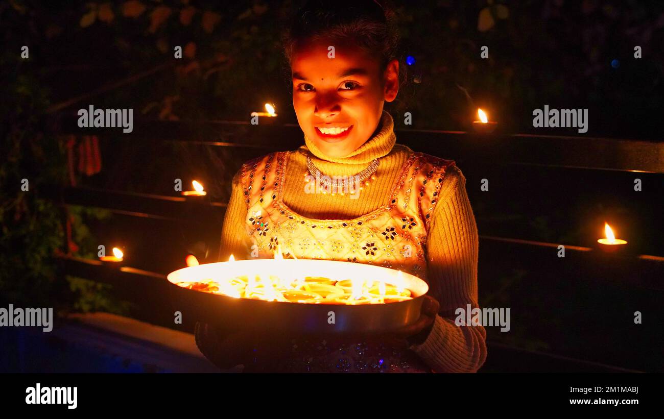 Many Diya or traditional clay lamps on Diwali festival. A girl hand ...