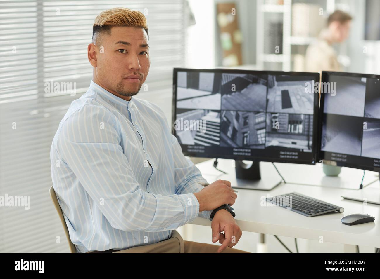 Side view portrait of young Asian man looking at camera with ...