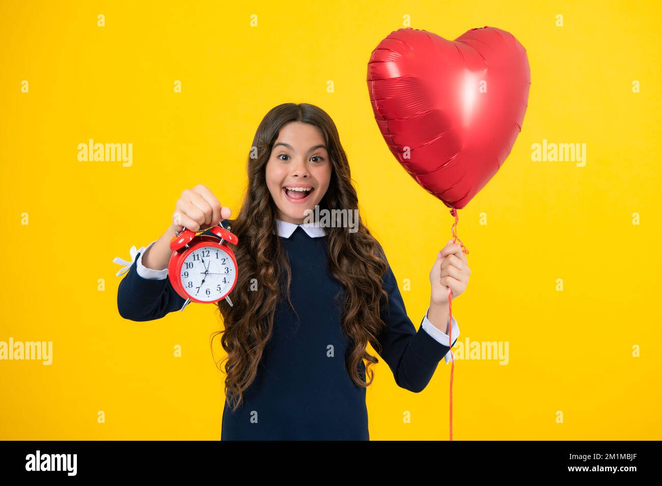 Teen student girl hold clock isolated on yellow background. Time to ...
