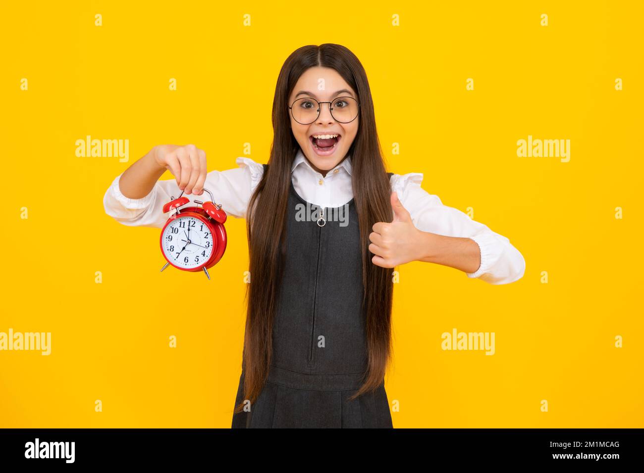 Punctual teen girl checking time. Child with alarm clock showing time ...