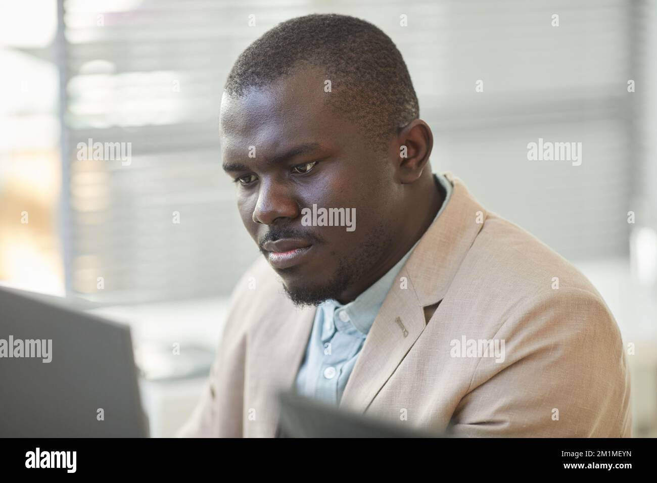 Close up of black man looking at computer screen while working in office cubicle Stock Photo - Alamy