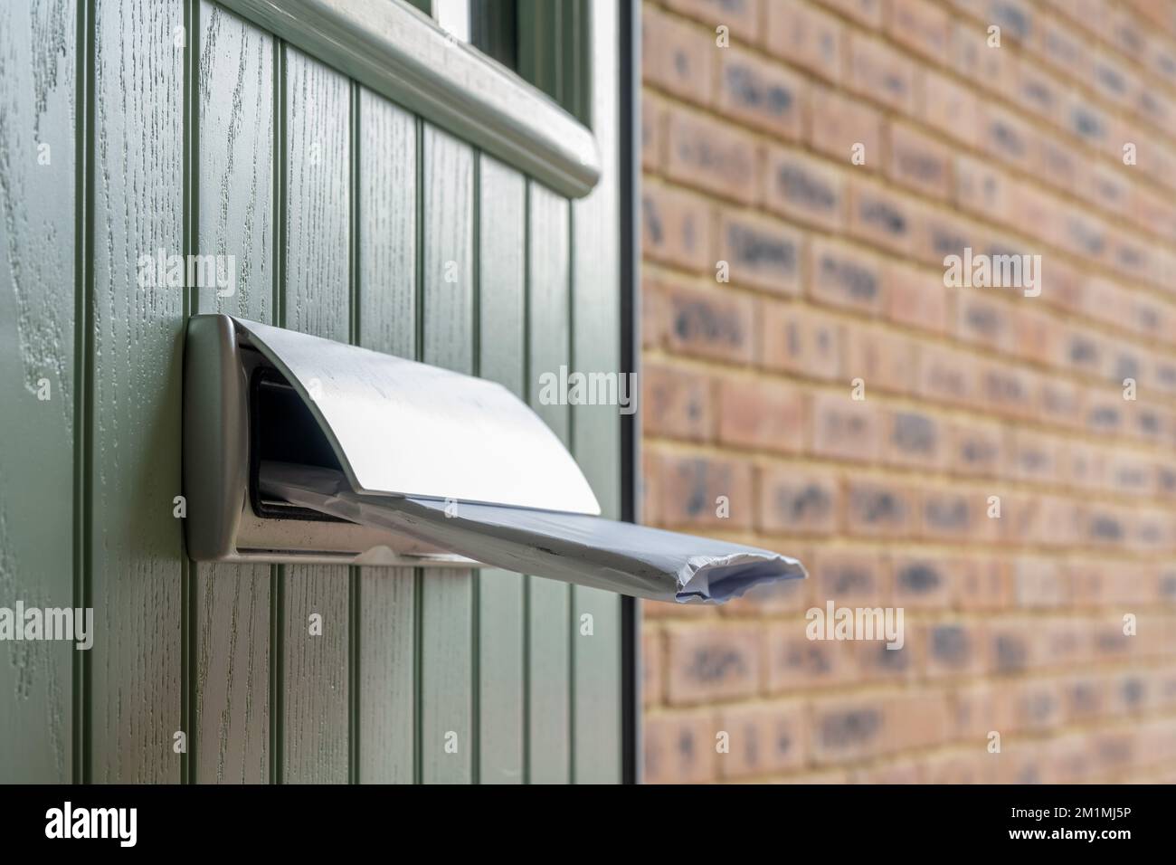 large white letter half pushed into the letter postal box of a domestic ...