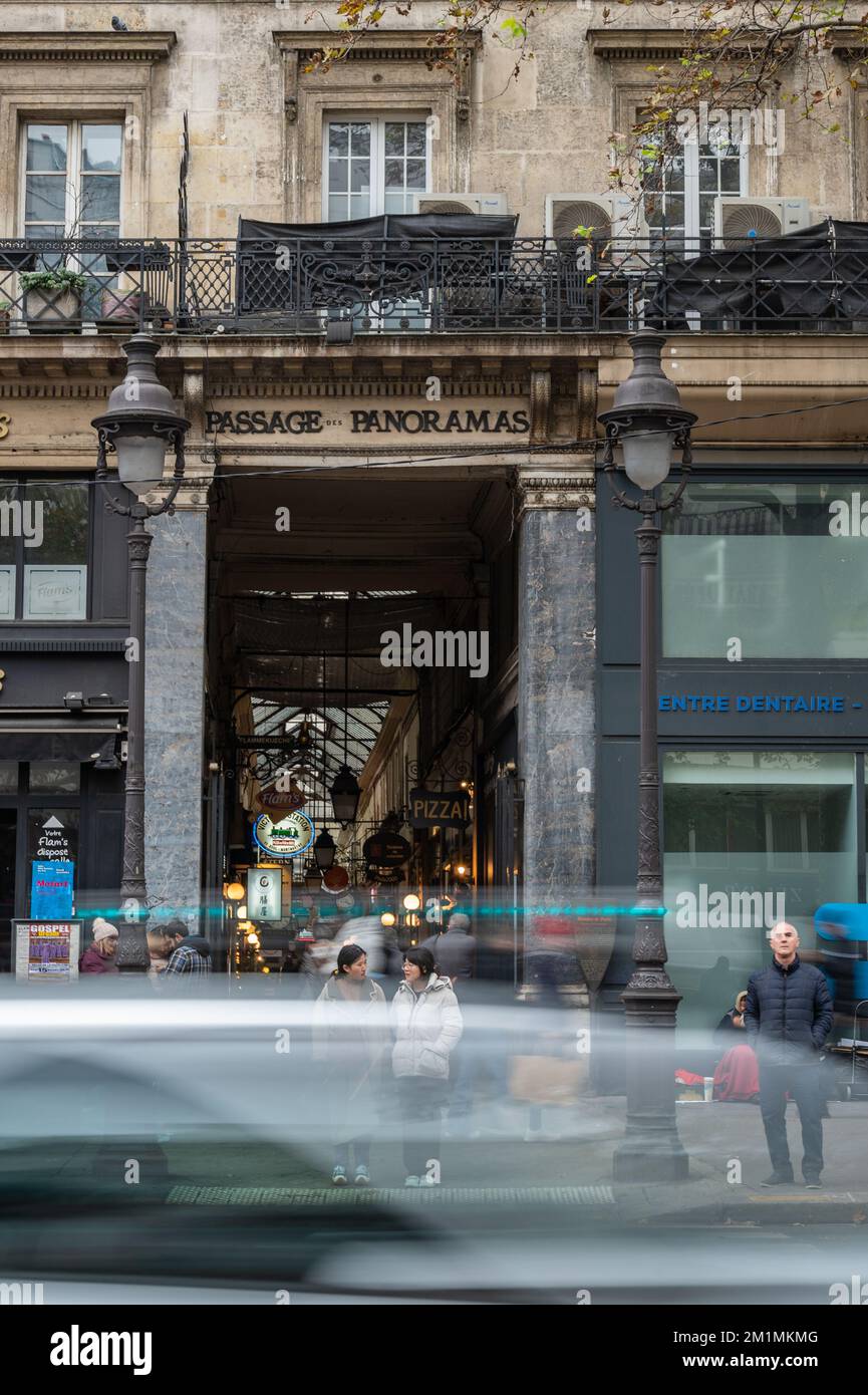 People stand on a busy street outside of Passage Panoramas, Paris, 2022 ...