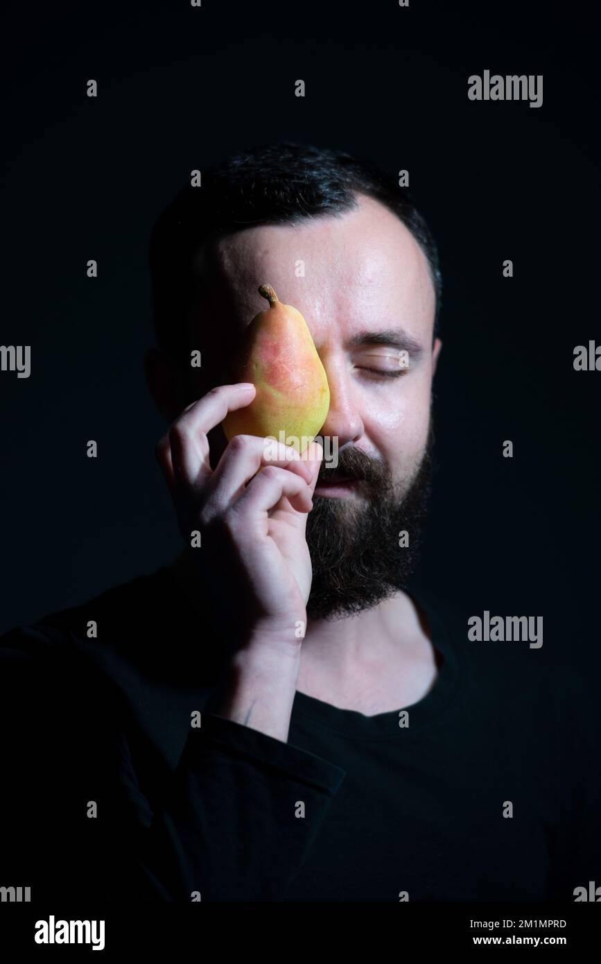 an authentic portrait of a bearded millennial covering his eye with a ...