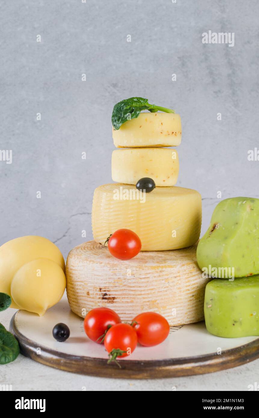 A pile of different kinds cheese heads stacked in vertical row on table ...