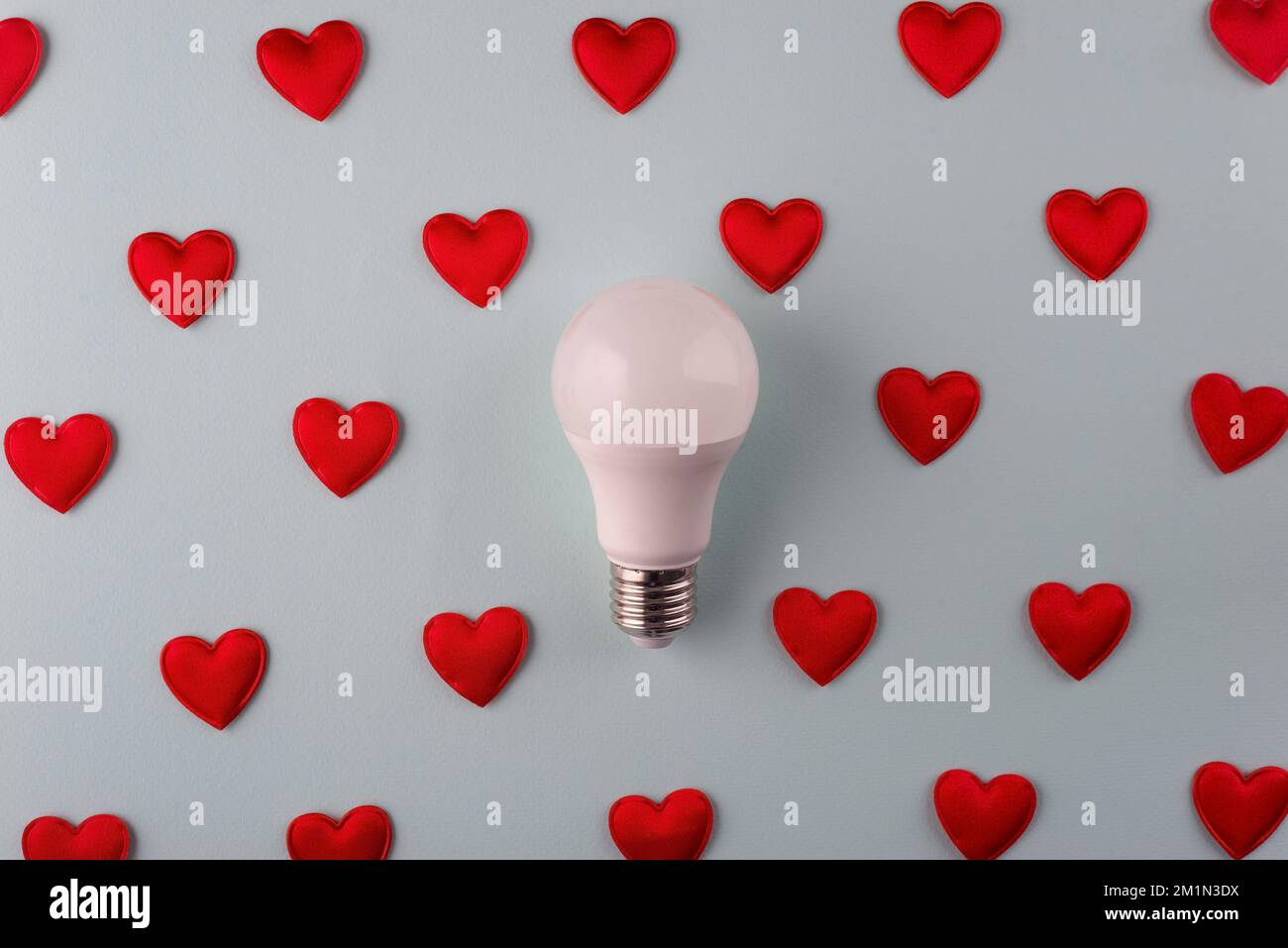 light love concept from hearts around light bulb on blue background ...