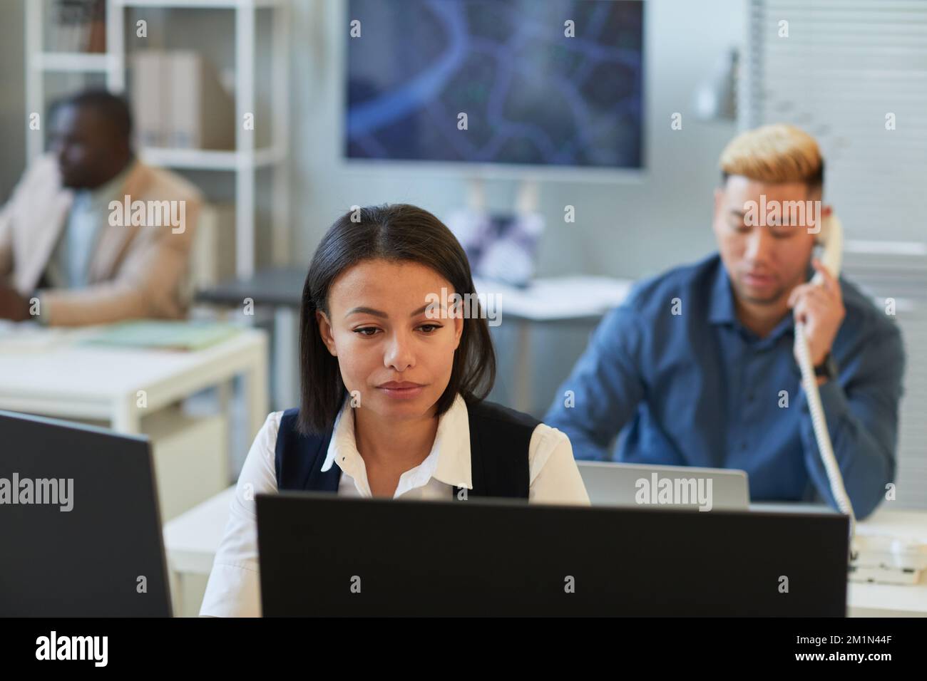 Front view portrait of black young woman looking at computer screen in ...