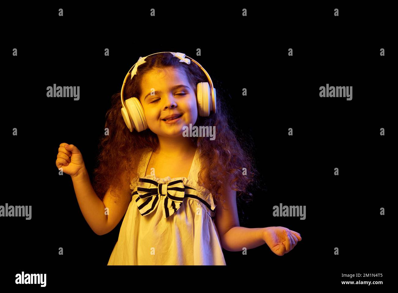 Charming cute little girl, emotional kid in headphones listening to ...