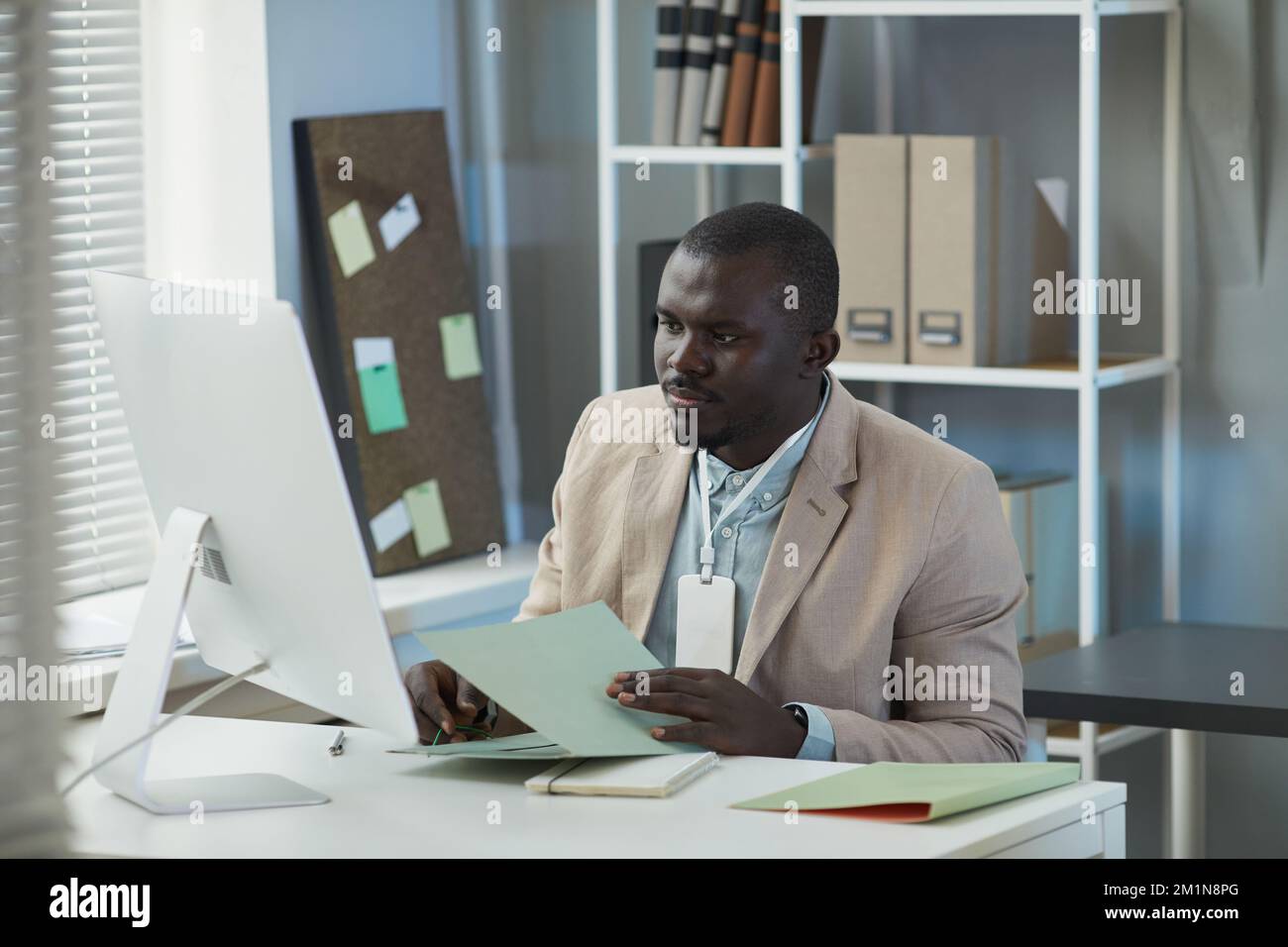 Portrait of black businessman using desktop computer in office and ...