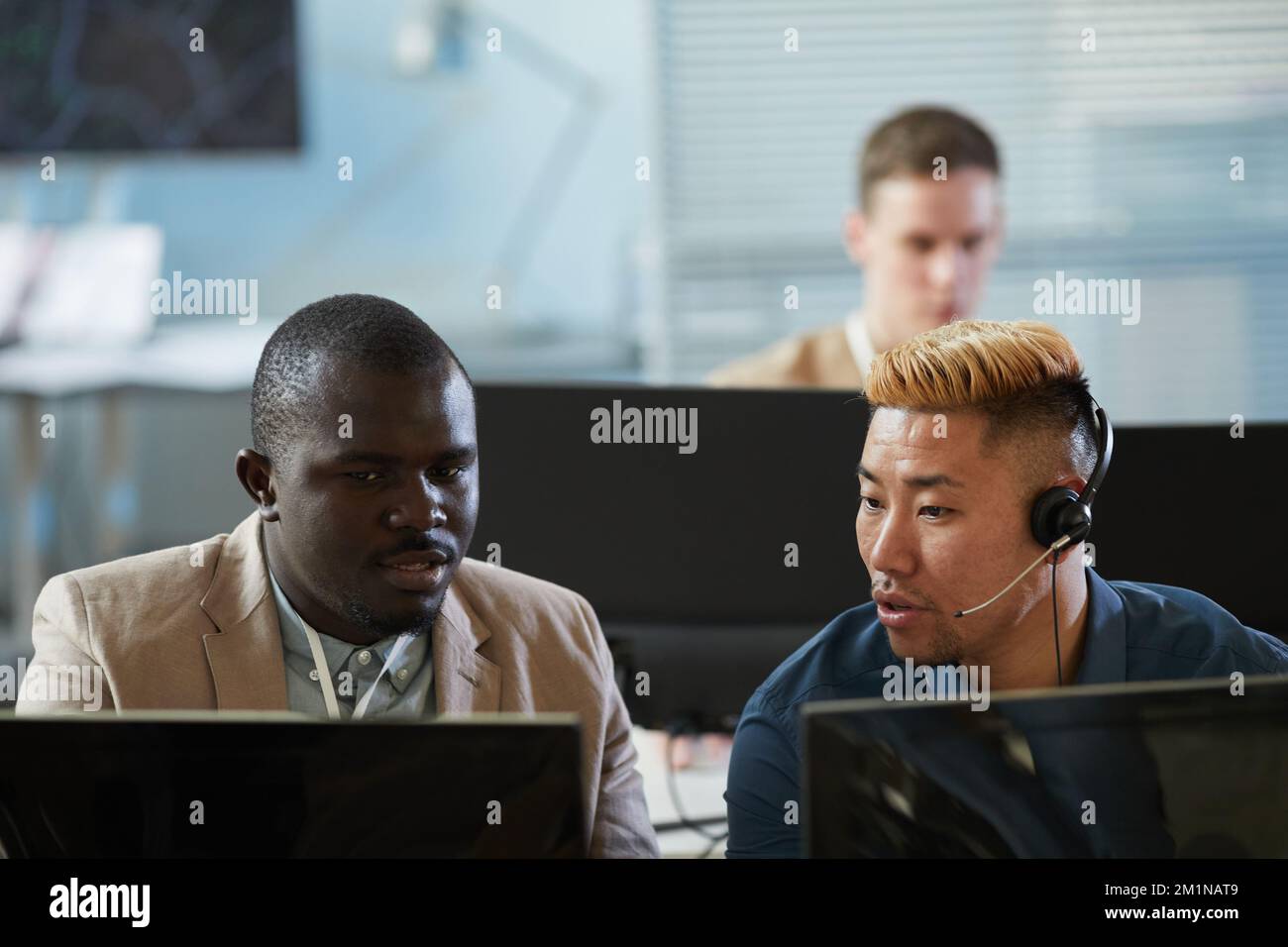 Front view portrait of two ethnic young men working in customer support ...