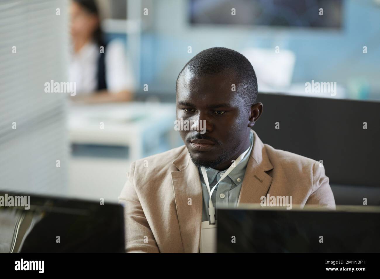 Portrait of focused black man looking at computer screen while working in office Stock Photo - Alamy