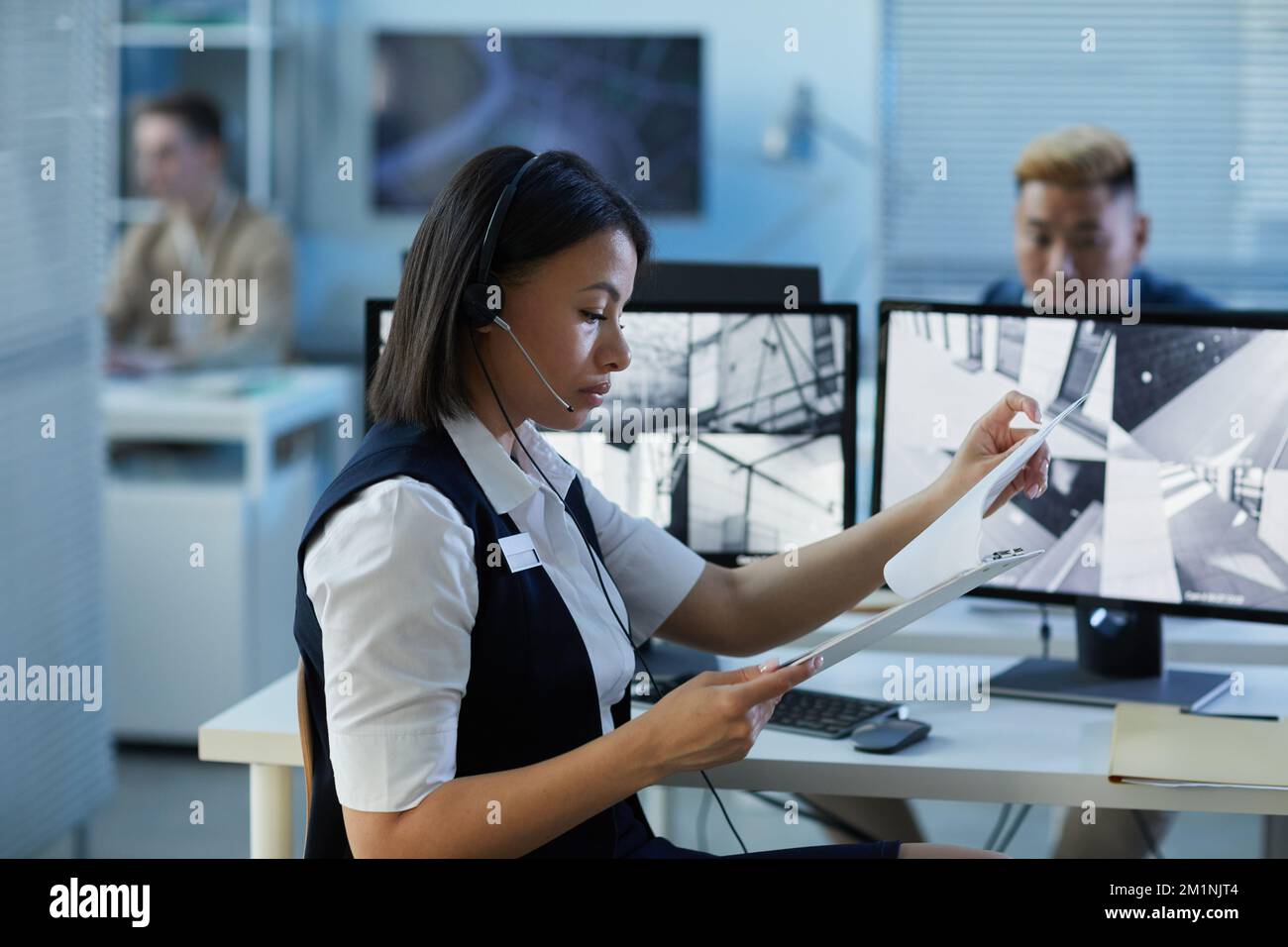 Side view portrait of young woman wearing headset in security center ...