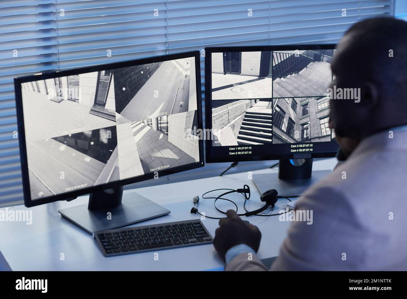 Back view black man looking at surveillance camera footage in security ...
