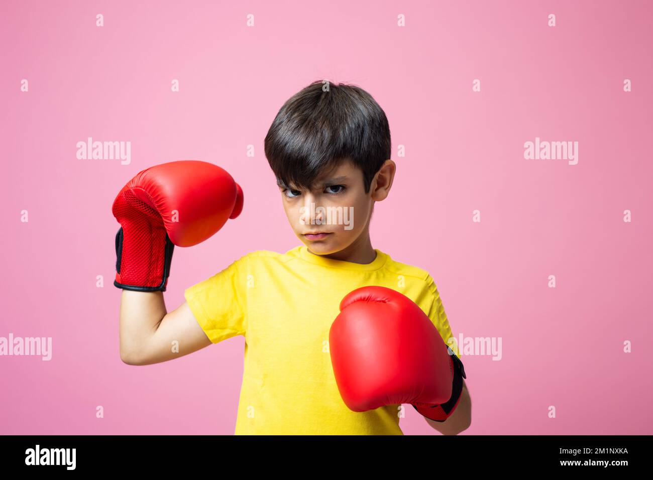 Studio portrait with pink background of a boy with boxing gloves ...