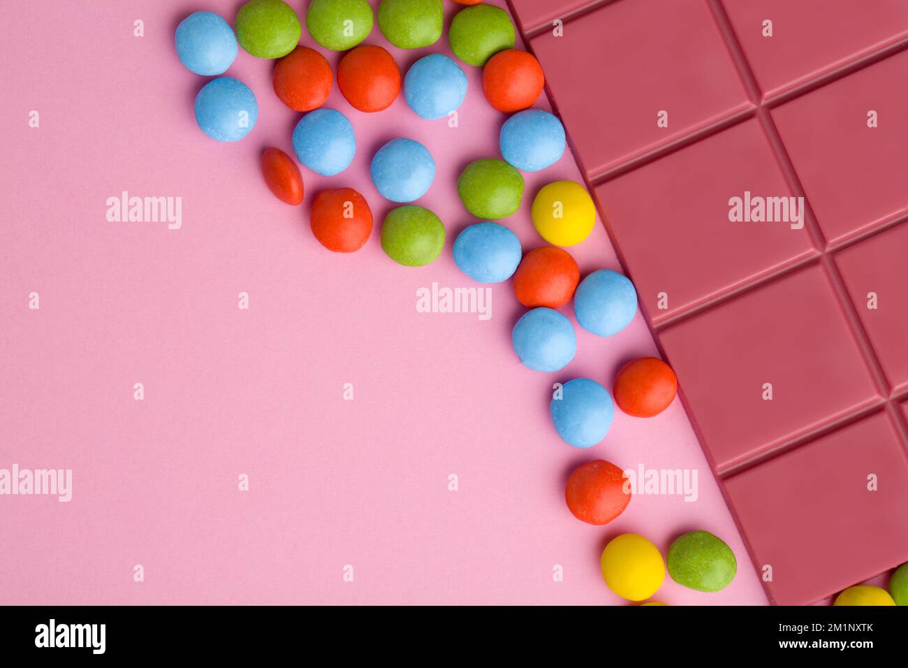ruby chocolate bar with colorful chocolate candy tablets on pink ...