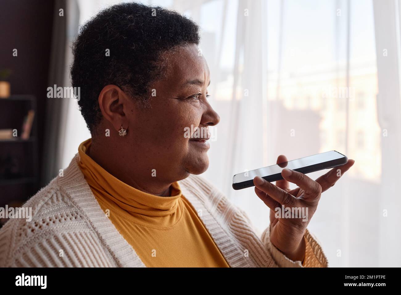 Side view portrait of black senior woman recording voice message via ...