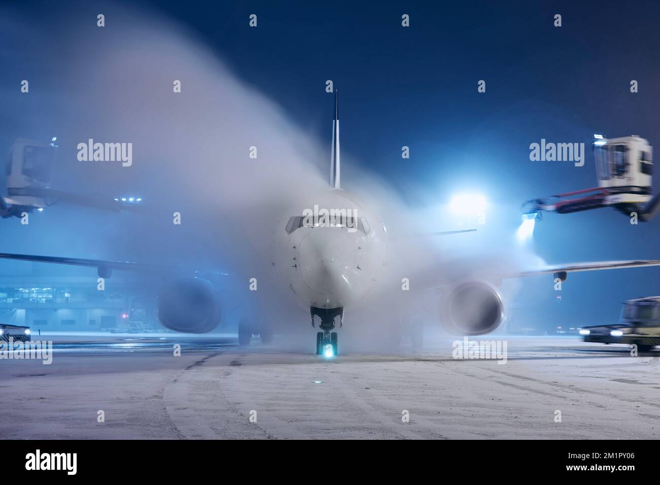 Deicing of airplane before flight. Winter night at airport during ...
