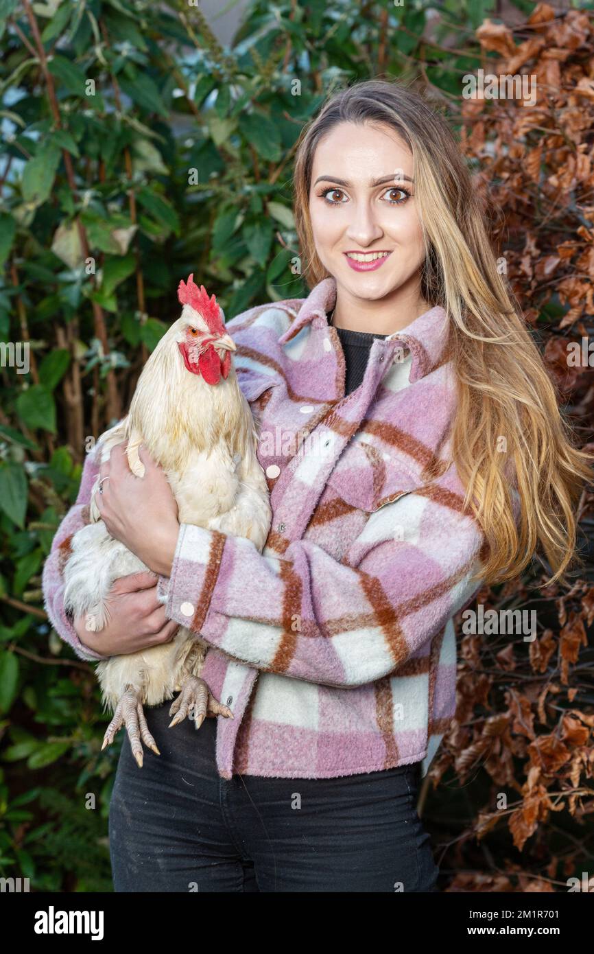 A young woman holding a rooster under her arm Stock Photo - Alamy