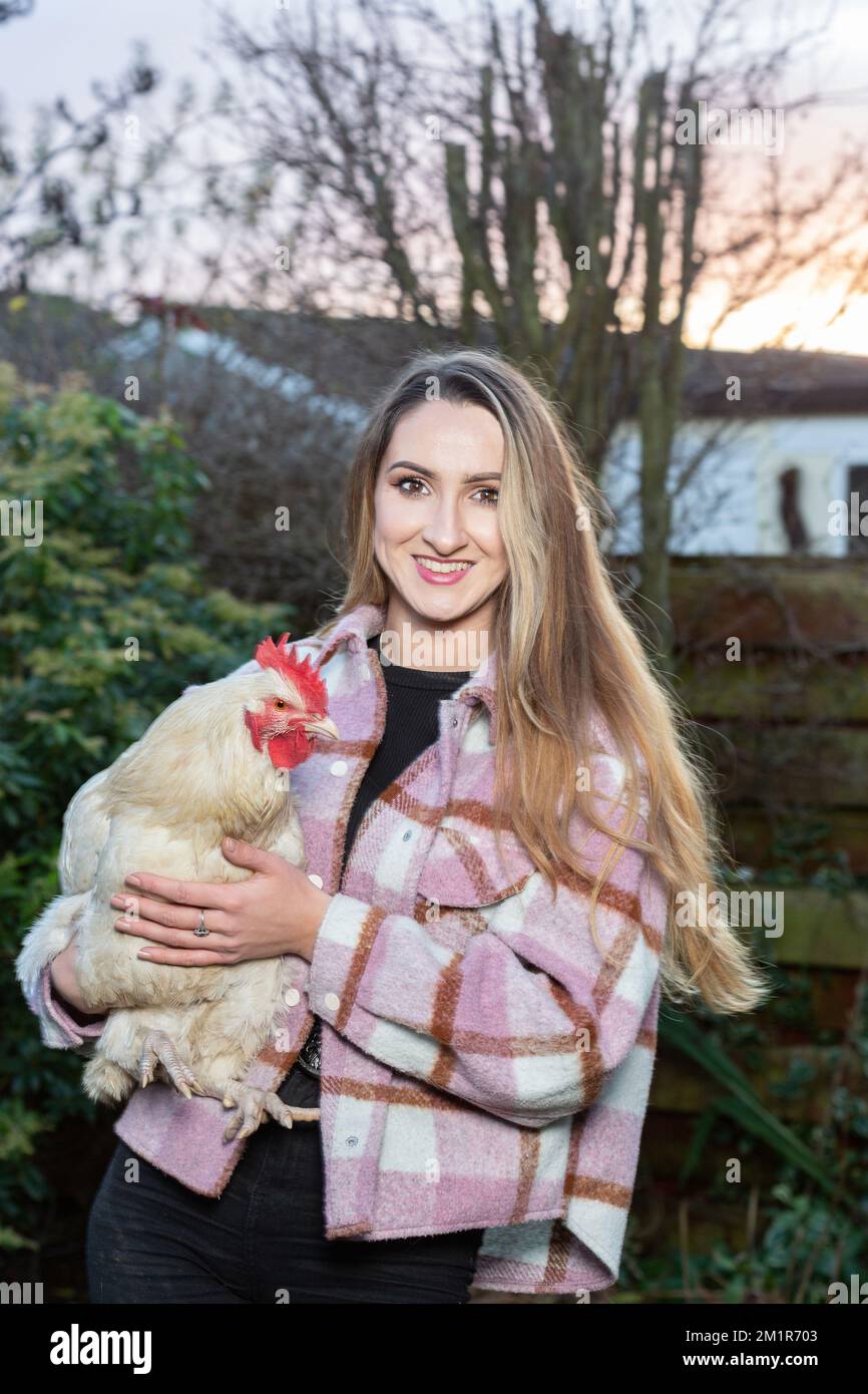 A young woman holding a rooster under her arm Stock Photo - Alamy