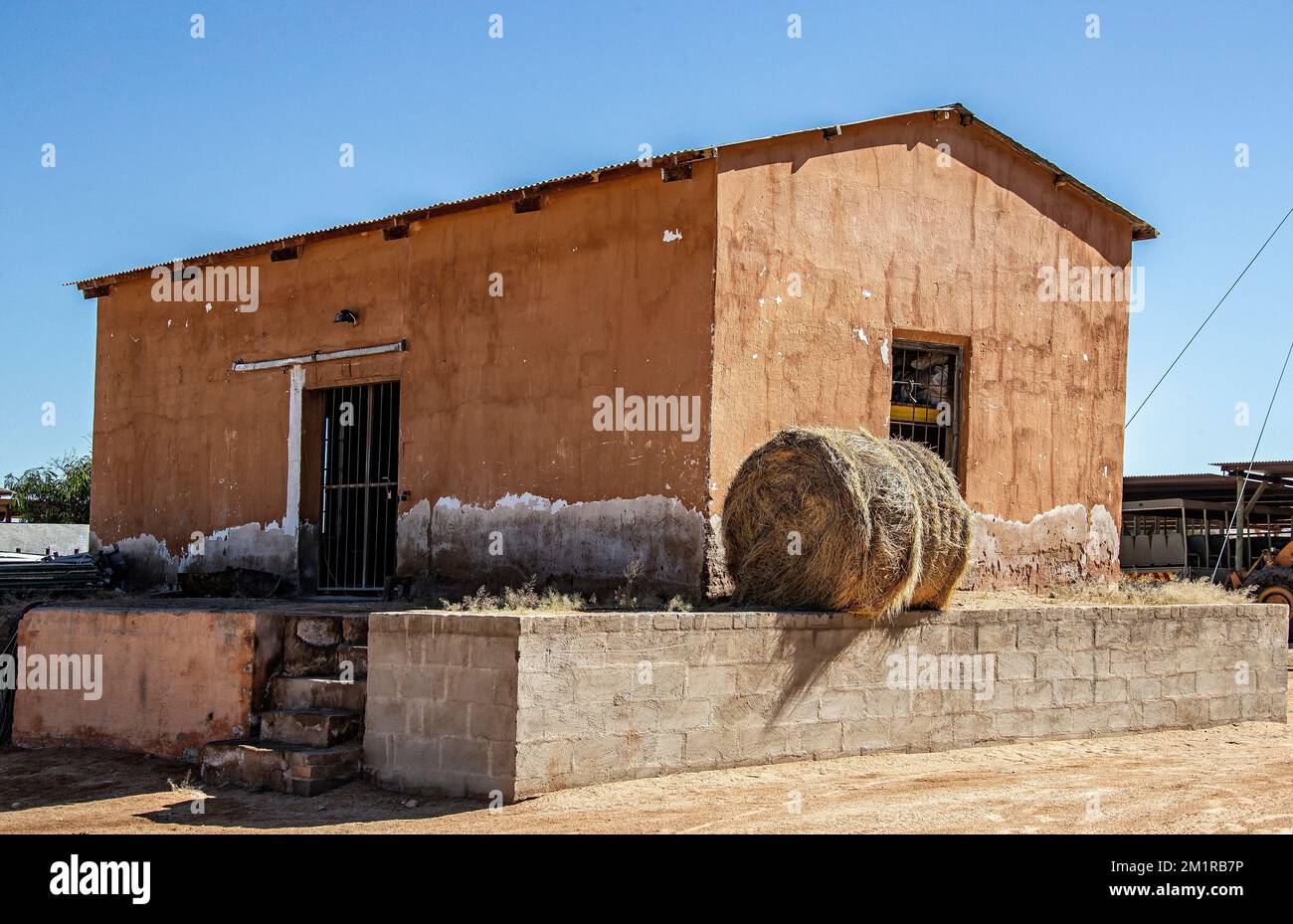 An old, terracotta building and a round hay bale at Solitaire in the ...