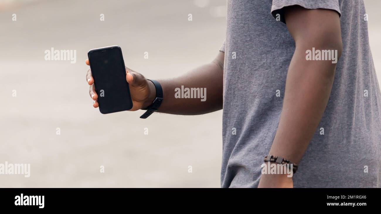 Hand of young black african man holding white blank screen smartphone ...