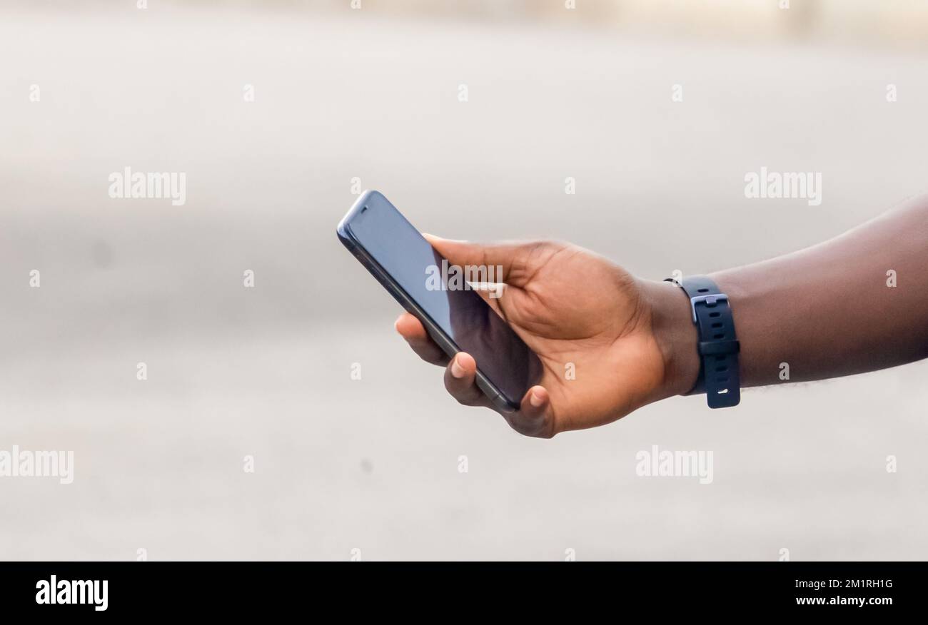 Hand of young black african man holding white blank screen smartphone ...
